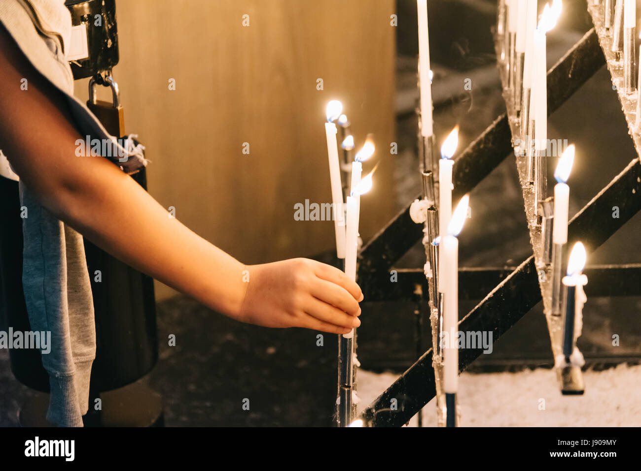 A young woman lighting the candles in a church. Horizontal composition ...