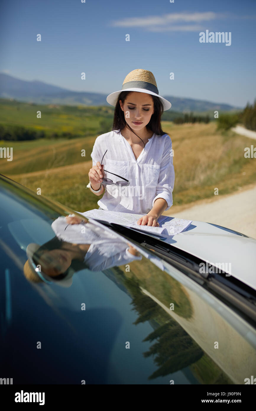 A tourist with a map at the car checks the route to the destination ...