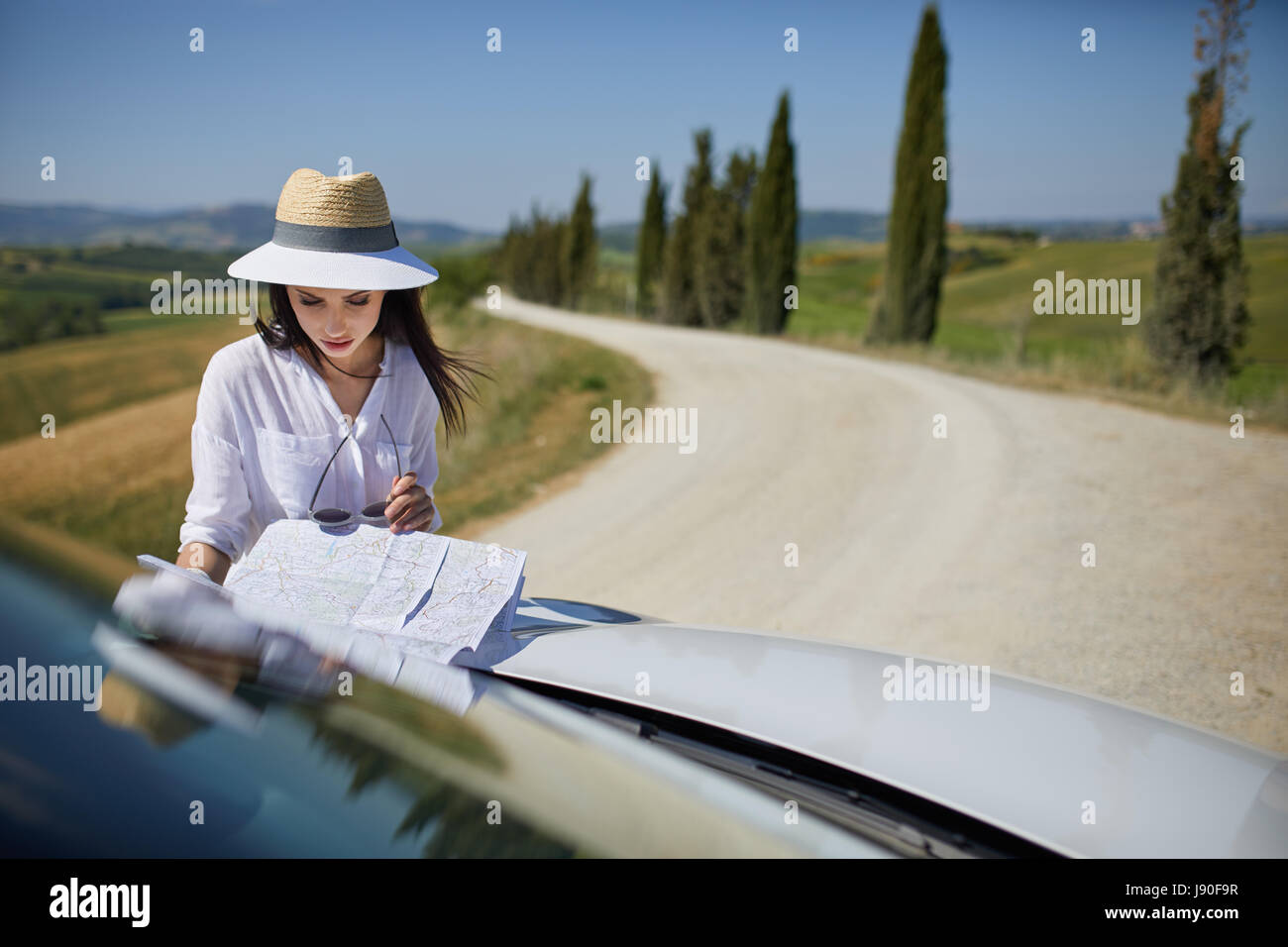 A tourist with a map at the car checks the route to the destination ...