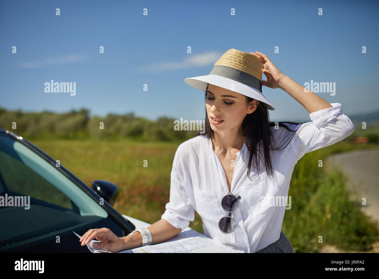 A tourist with a map at the car checks the route to the destination ...