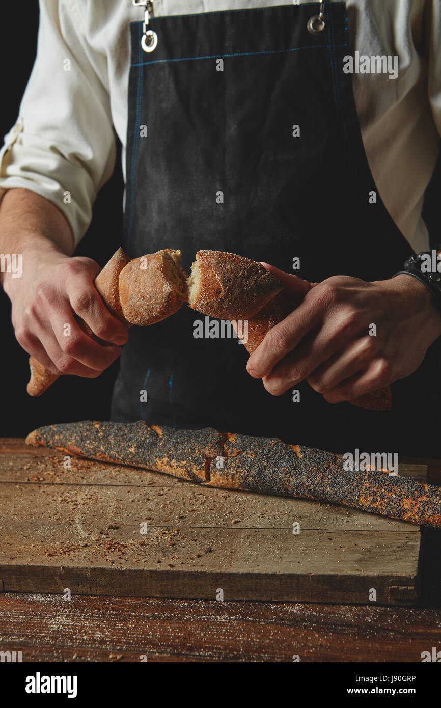 Hand breaks baguette Stock Photo - Alamy