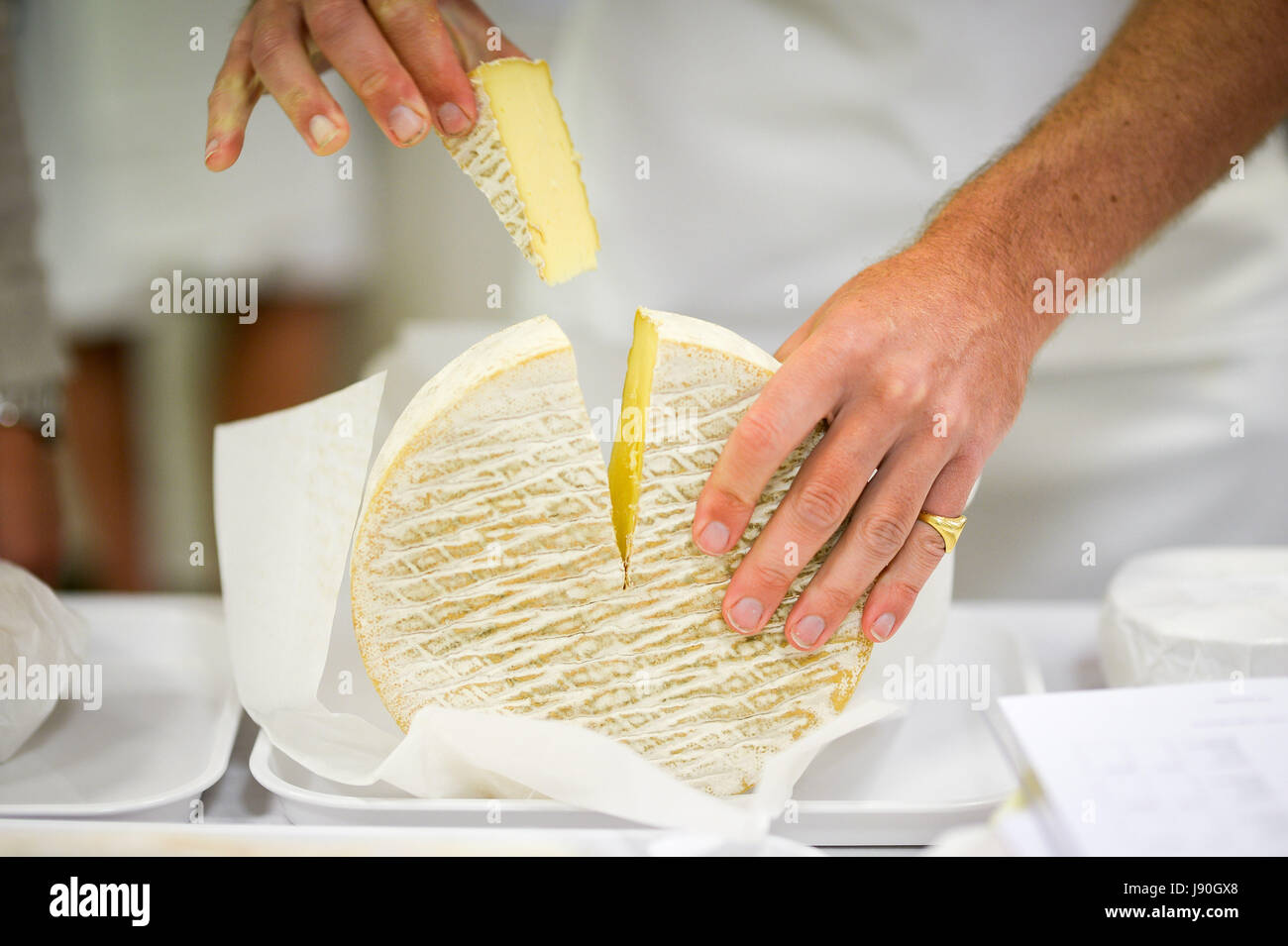 A slice of soft cheese is cut and removed for tasting during the ...