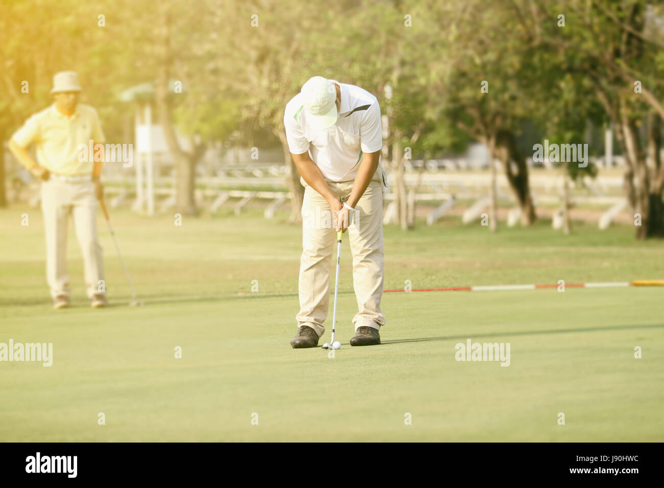 Asian golfers hit sweeping and keep golf course in the summer for relax ...