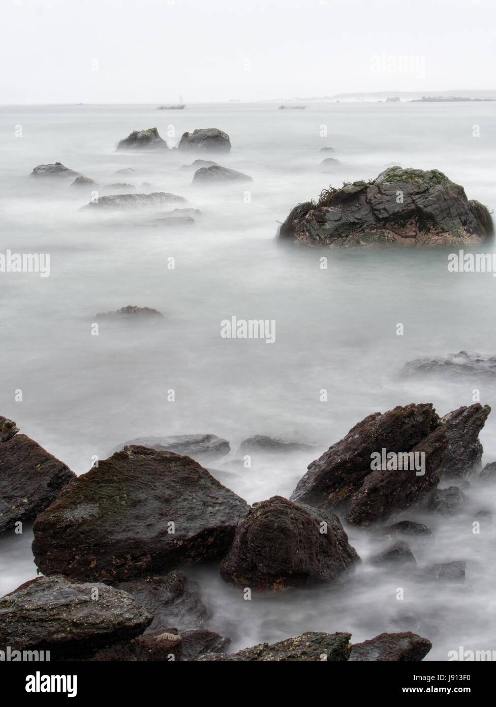 Blurry waves and rocks on grey morning coastline at Isla Damas, La ...