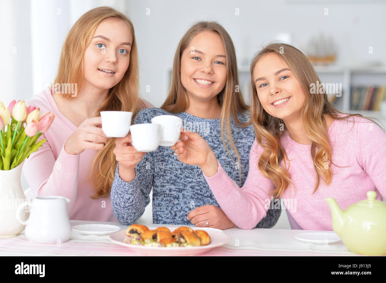 Teenage girls sitting at table and drinking tea with cookies Stock ...