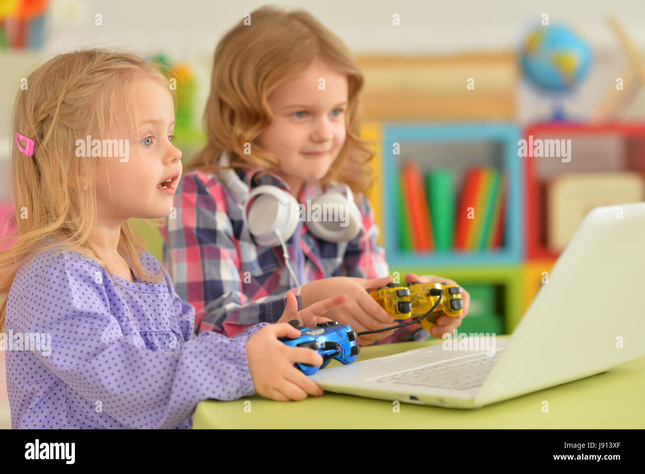 Two cute little sisters playing computer game with joysticks Stock ...