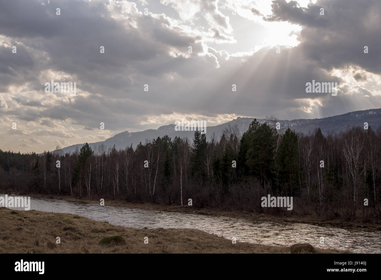 The spring river flows at the foot of the mountain ridge Stock Photo ...