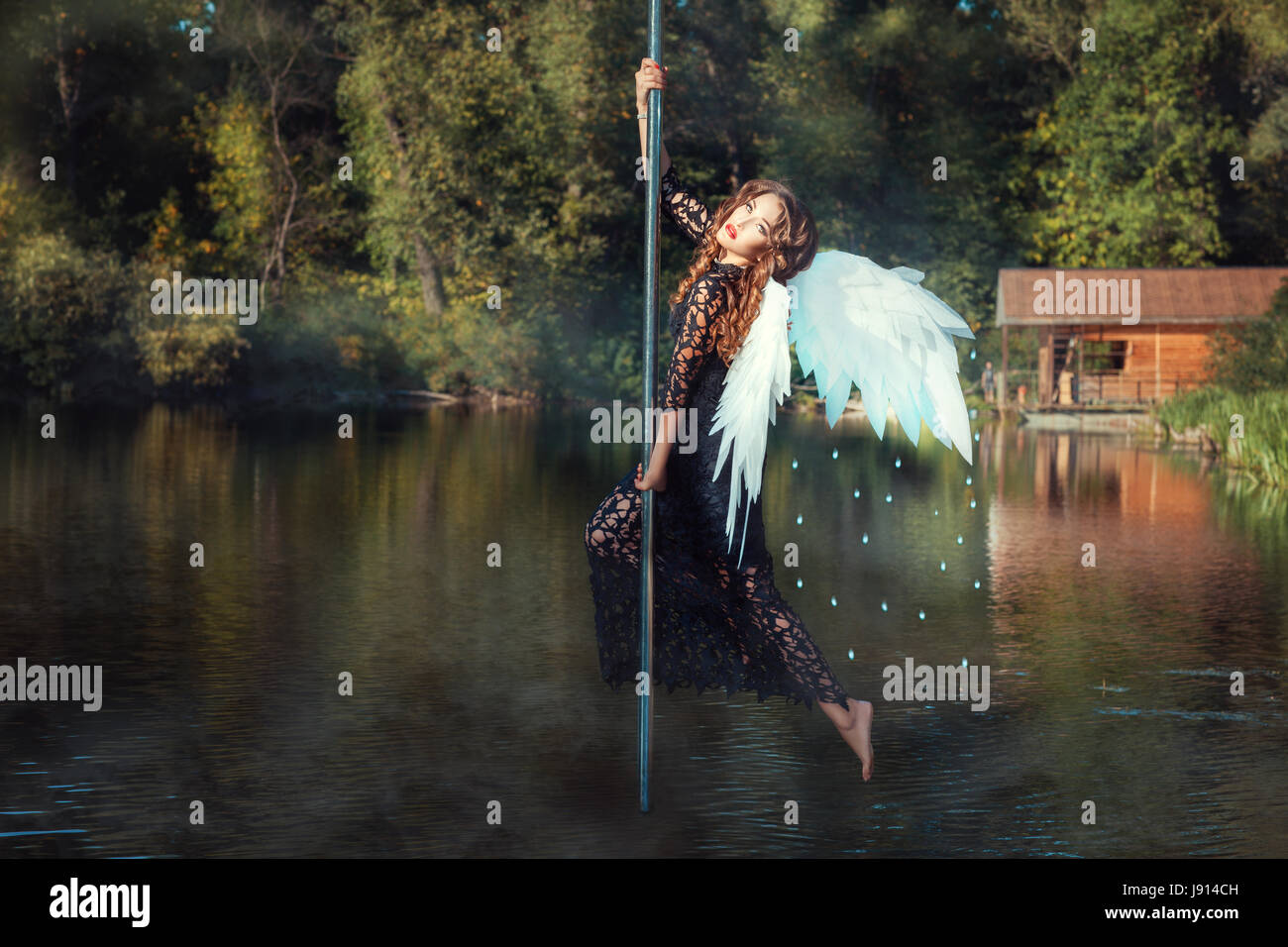 Girl with angel wings dancing on the pole. Pole dance in the middle of ...