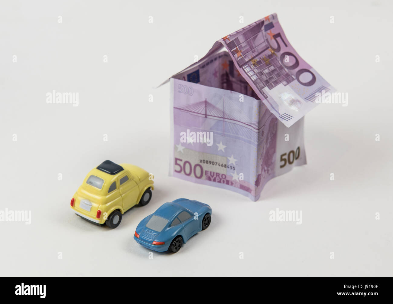 House made with 500 euro banknotes and cars parked outside isolated on ...