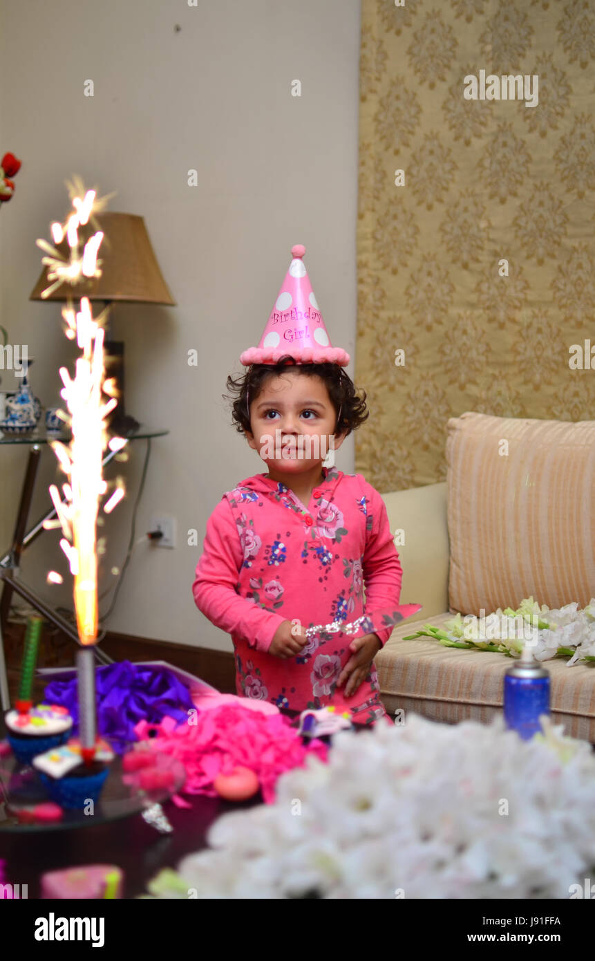 A girl enjoying while blowing candles and cutting her birthday cake ...