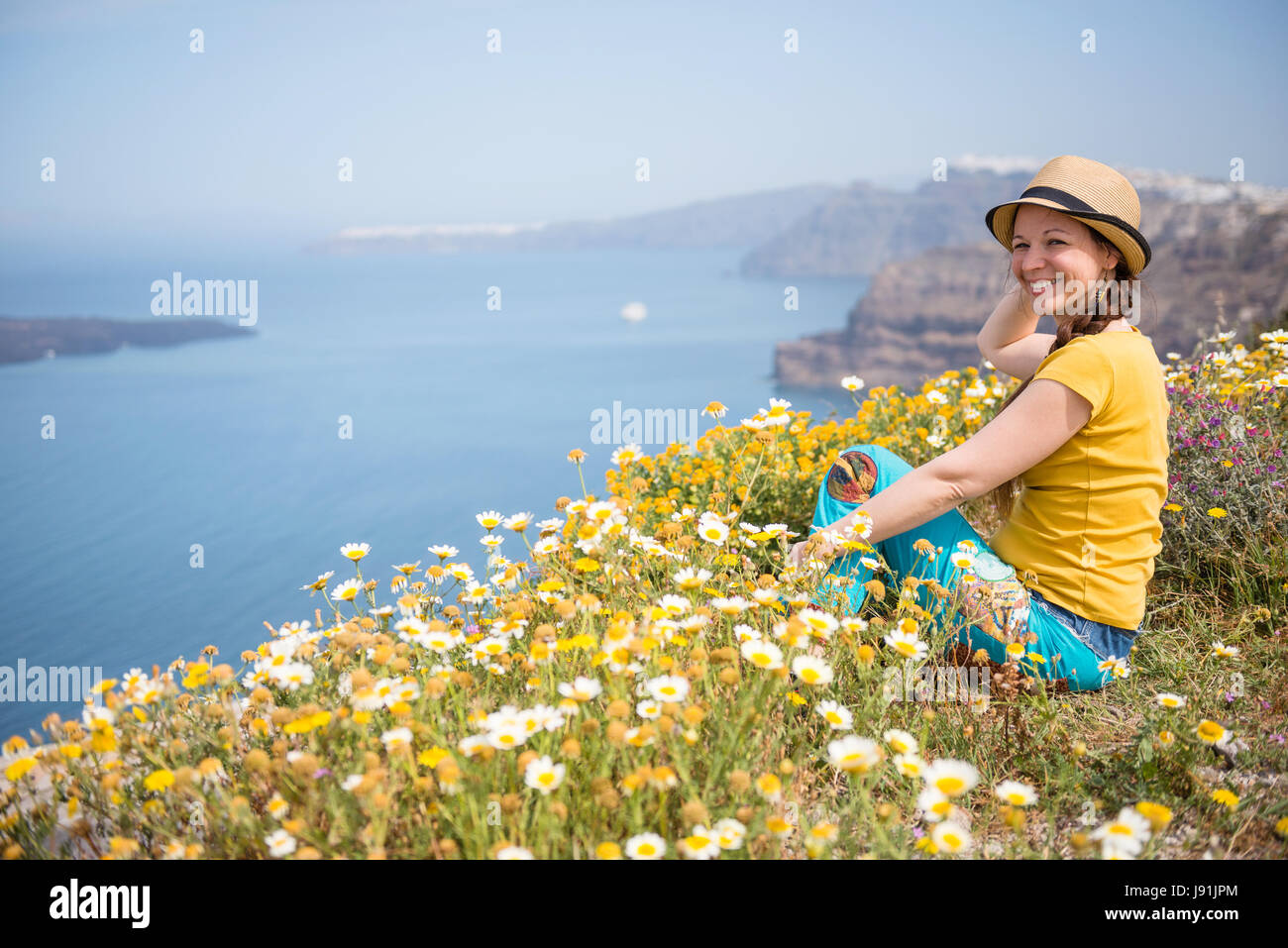 Young woman on the meadow full of flowers, Santorini, Greece Stock ...
