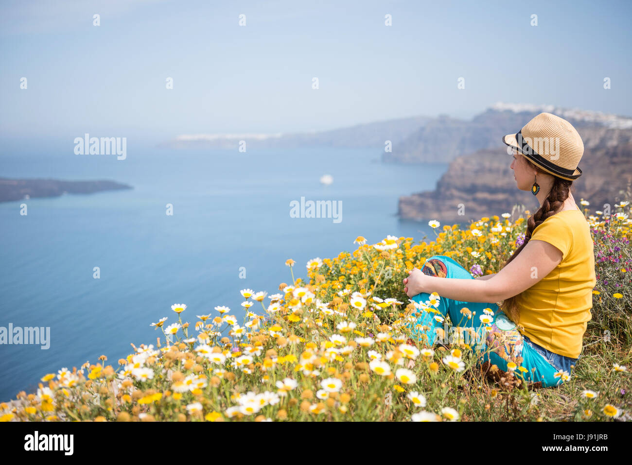 Young woman on the meadow full of flowers, Santorini, Greece Stock ...