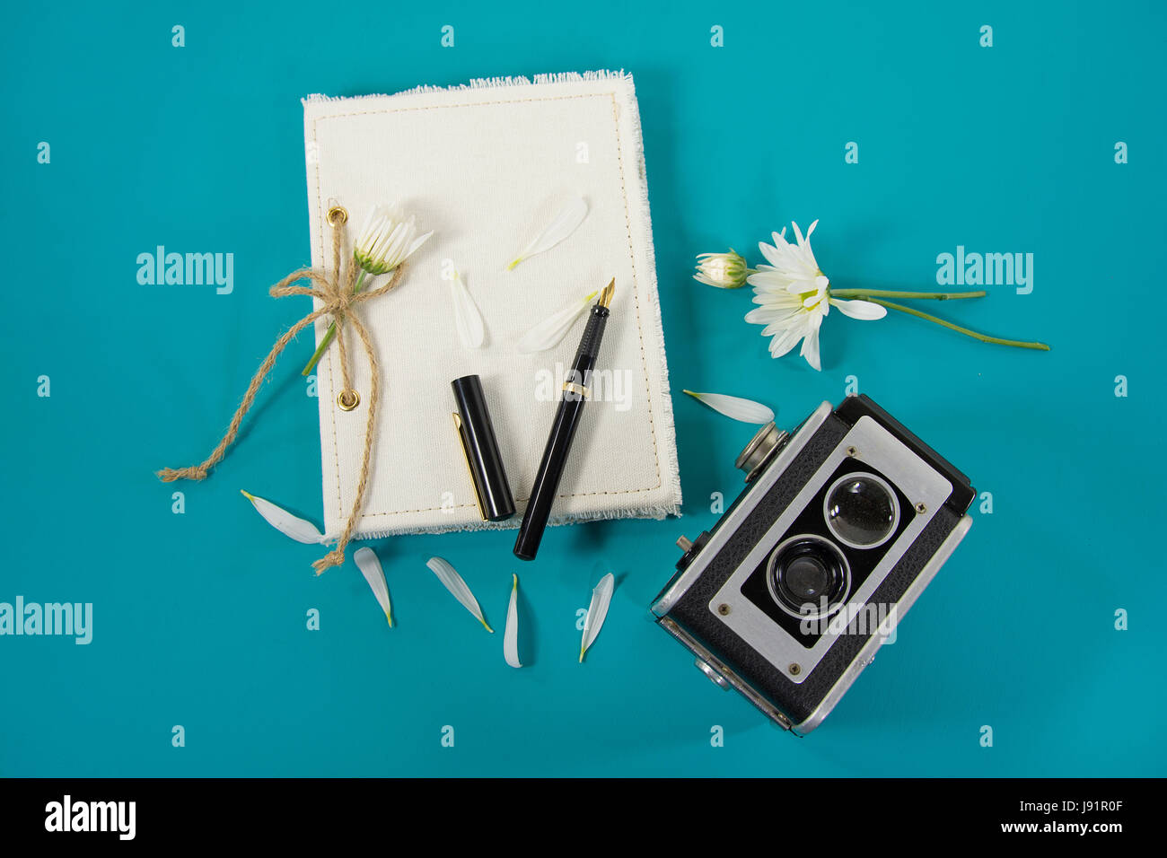 vintage camera and journal on turquoise painted wood with pen and white ...