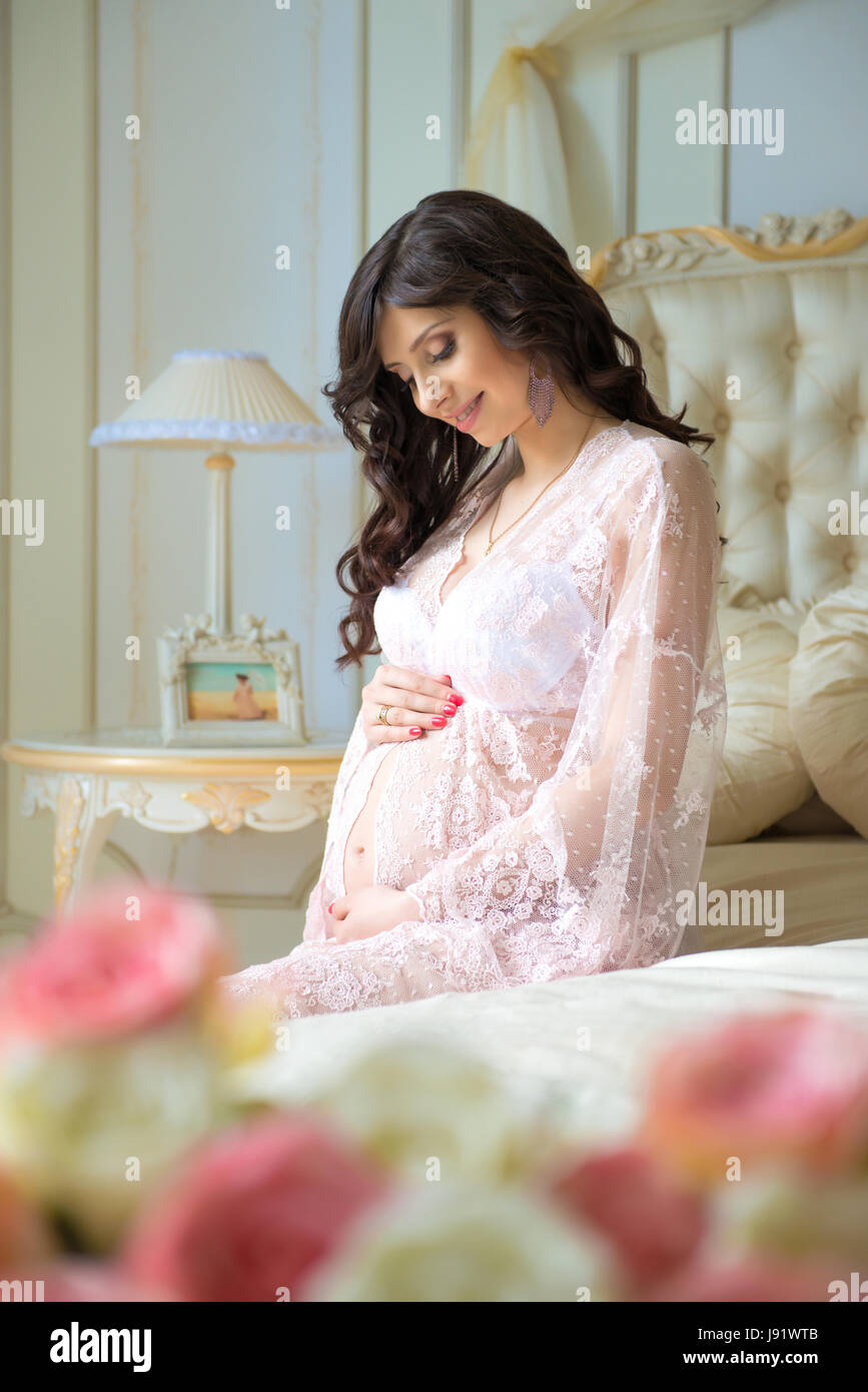 Beautiful Pregnant Girl In A Lace Negligee Sitting On A Bed Of Roses