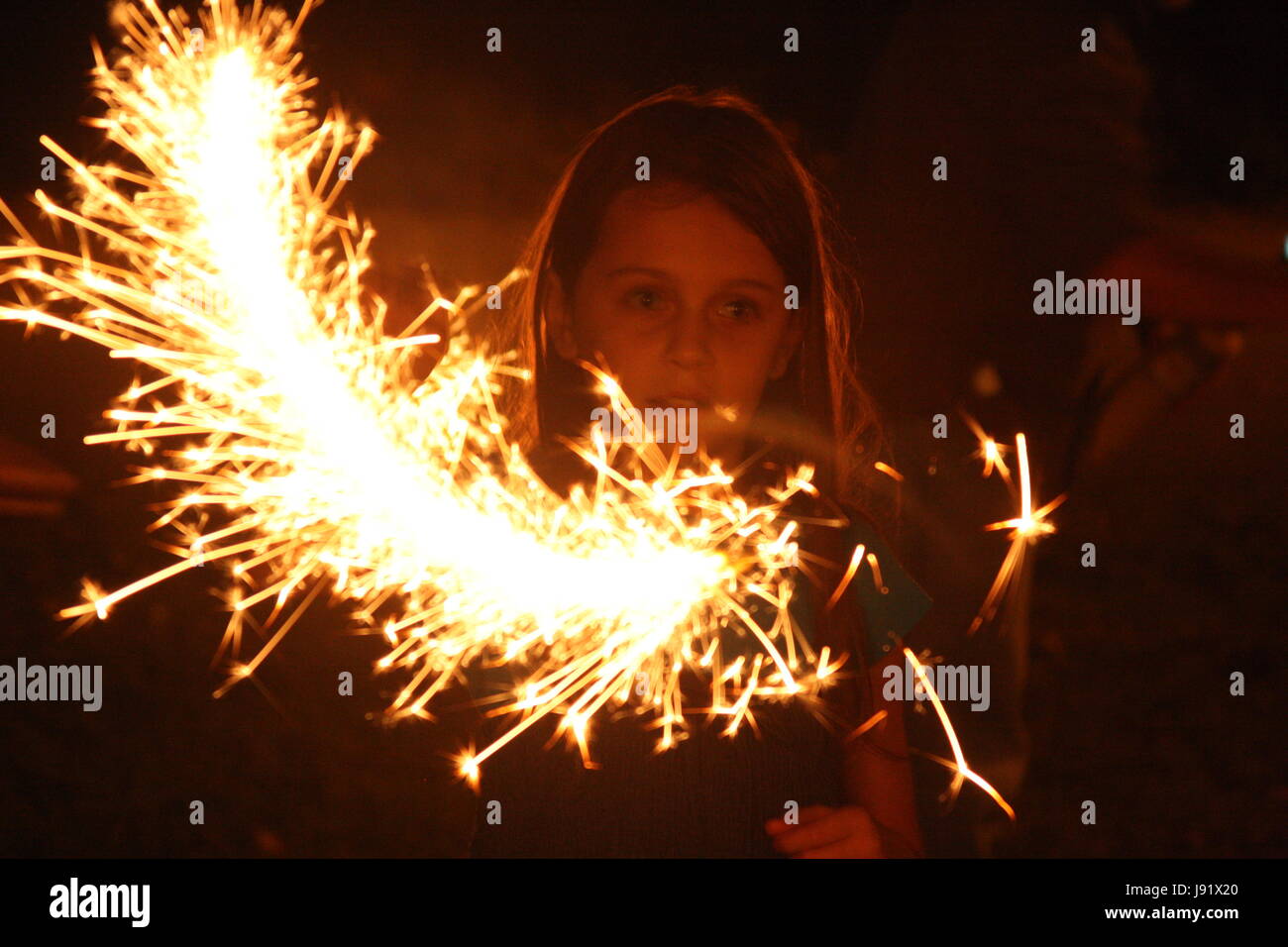 Girl holding a firecraker during event in the dark Stock Photo - Alamy