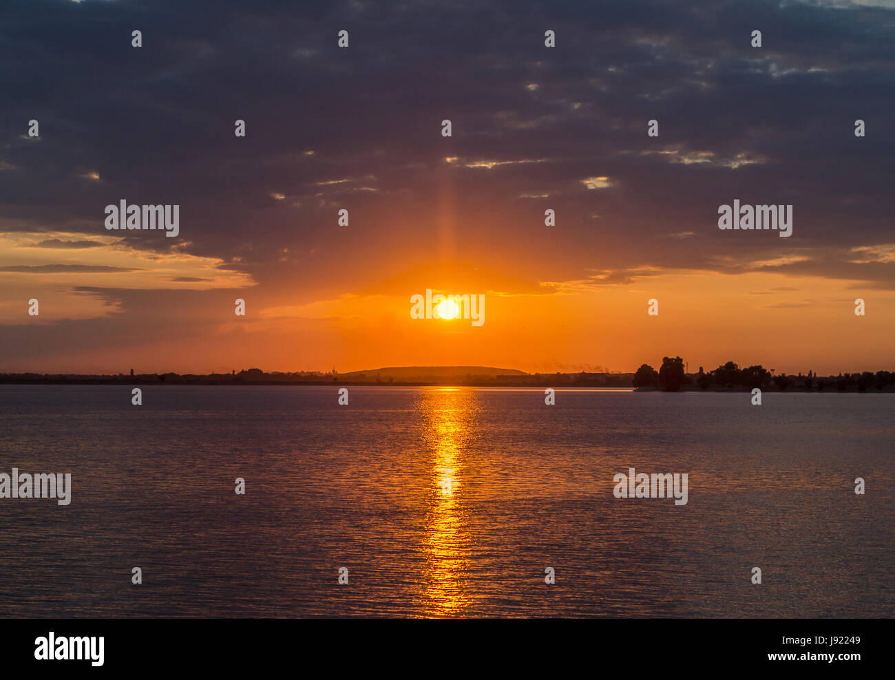 Orange sunset over a european lake, blue clouds sky, colored dramatic ...