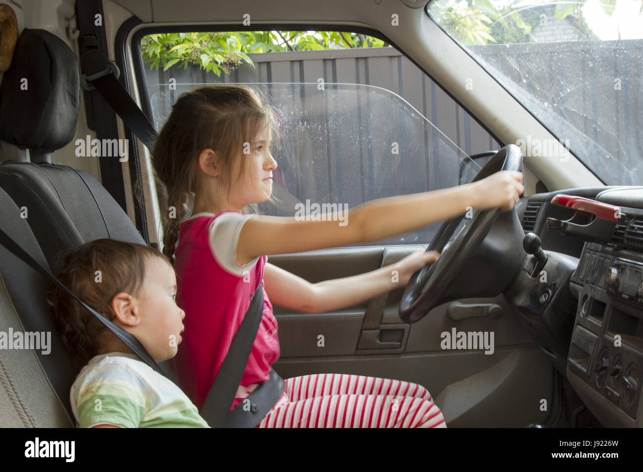 Smiling little brother and sister driving by toy car Stock Photo - Alamy