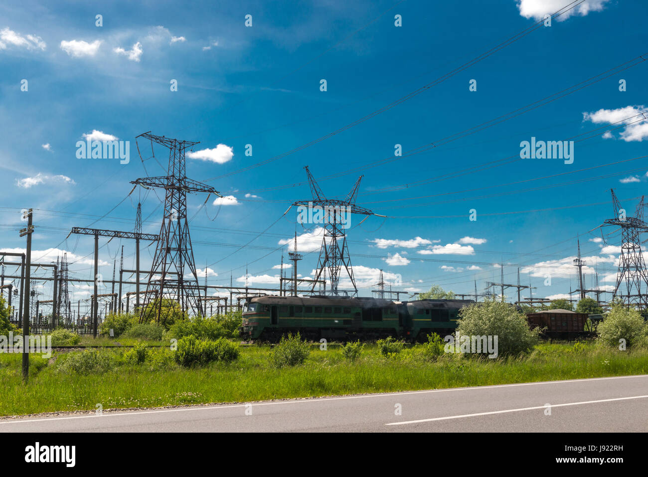 Freight train is passing by thermal power stations and power lines ...