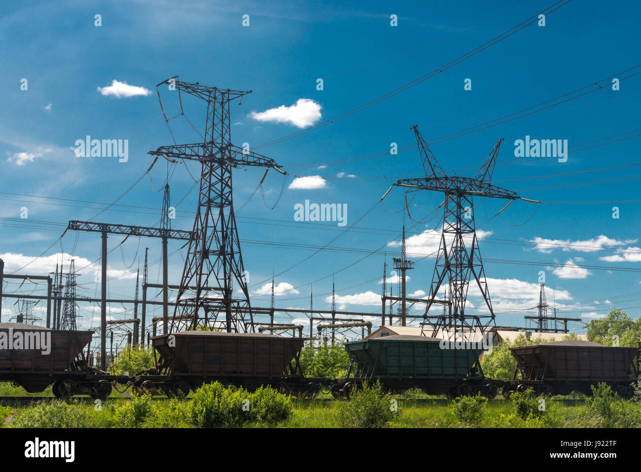 Freight train is passing by thermal power stations and power lines ...