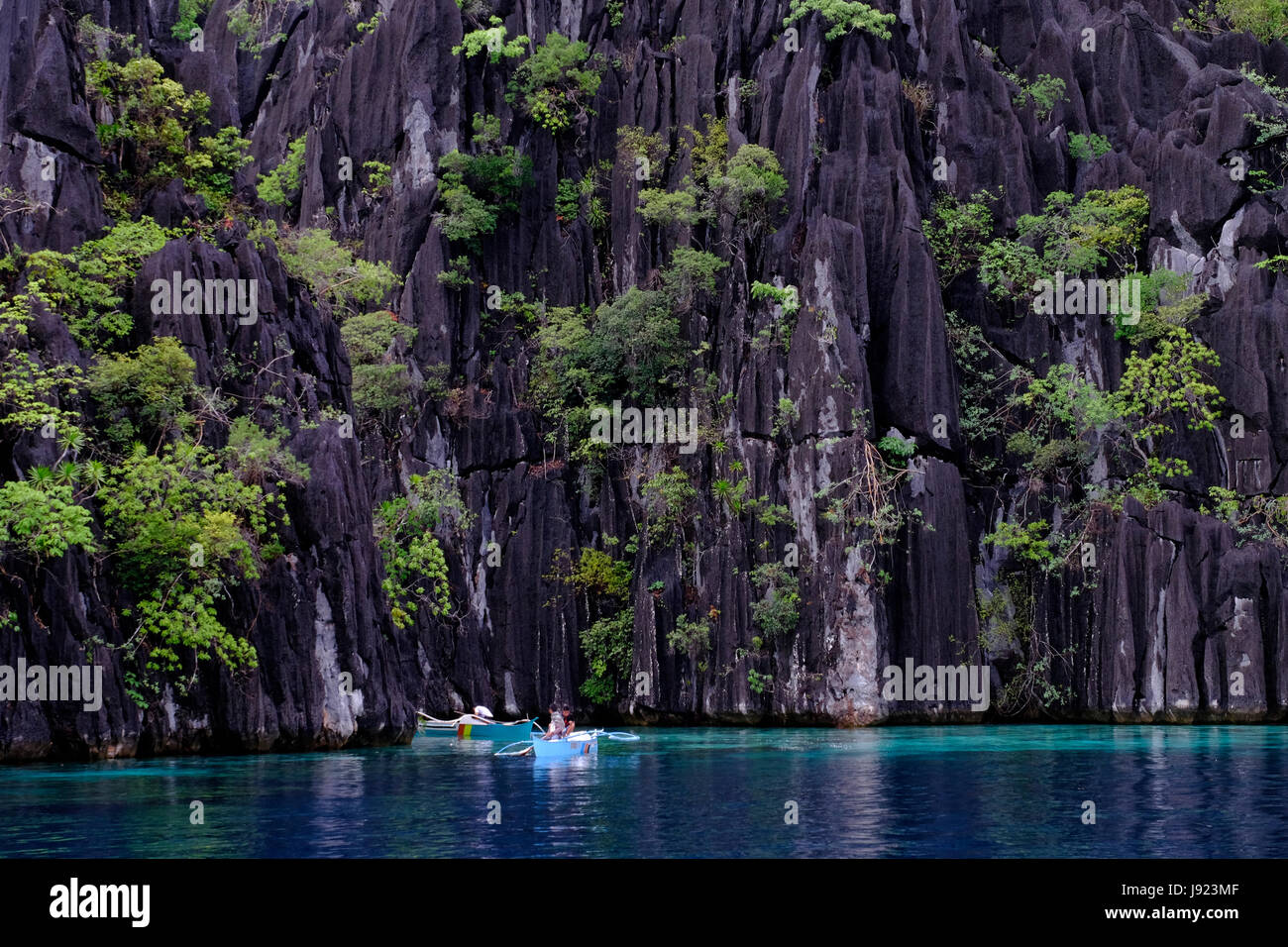 Filipino fishermen boating along steep cliff Karst rock formations near ...