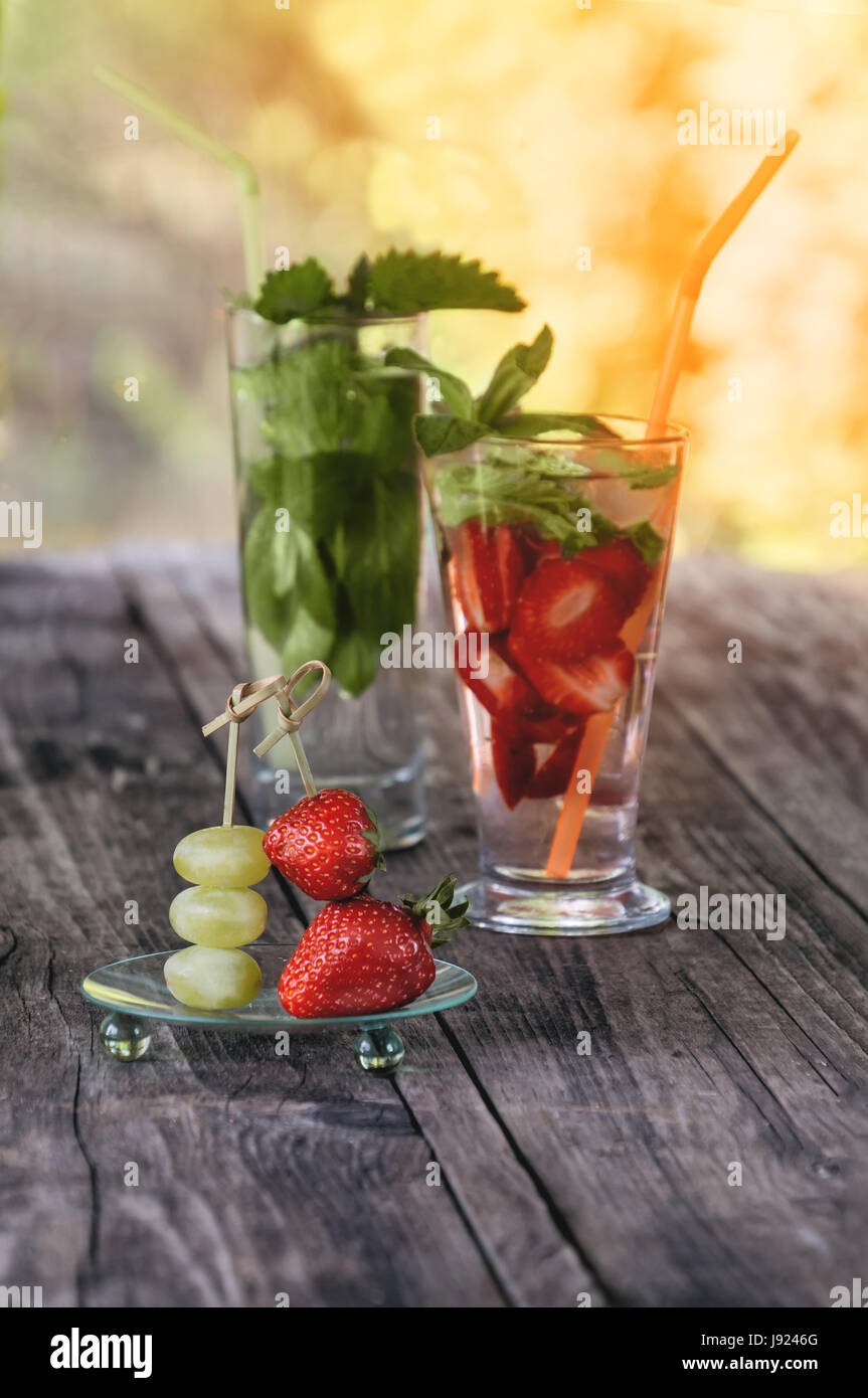 Strawberries and grapes on a skewer on the glass background with ...