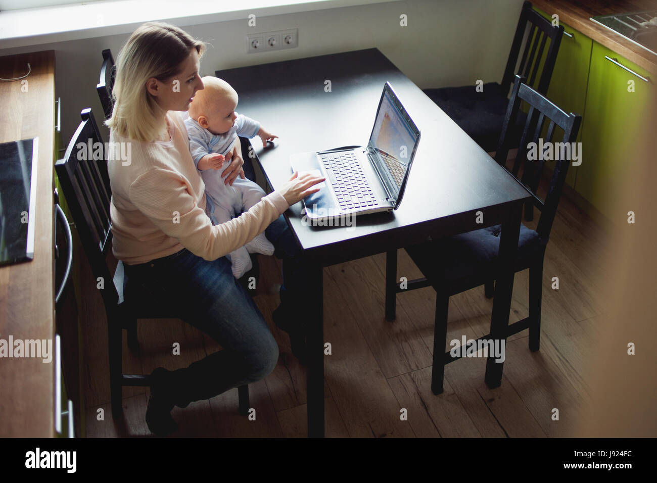 Young mother in home office with computer and her baby. Freelancer or ...