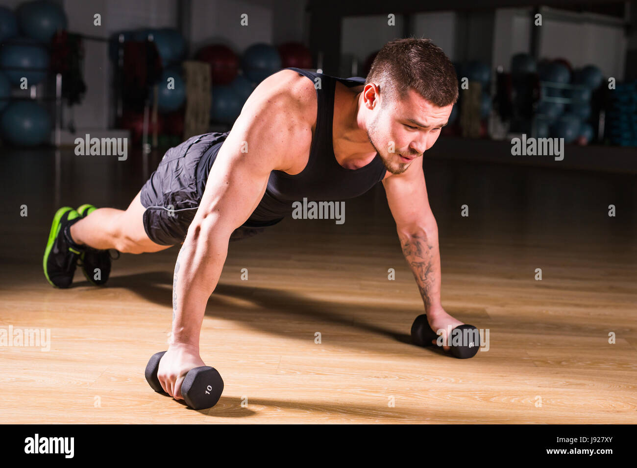 Gym man push-up strength pushup exercise with dumbbell in a fitness ...