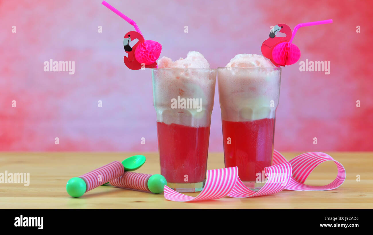 Making ice cream soda floats with pink raspberry soda and ice cream in ...