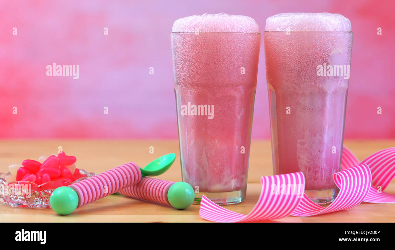 Making ice cream soda floats with pink raspberry soda and ice cream in ...