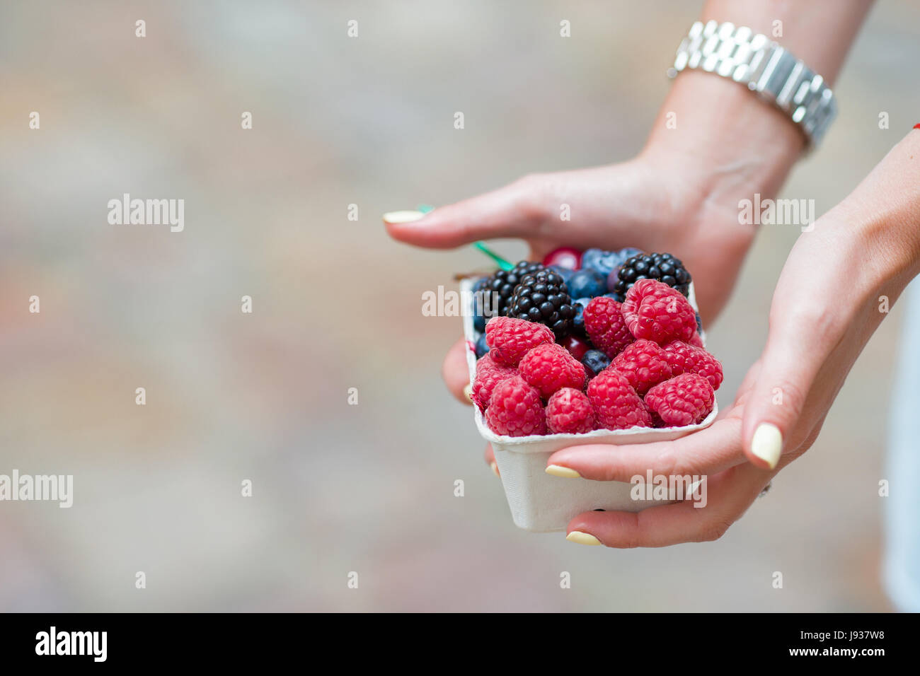Close up berries fruits at female hands. Blueberries, raspberries ...