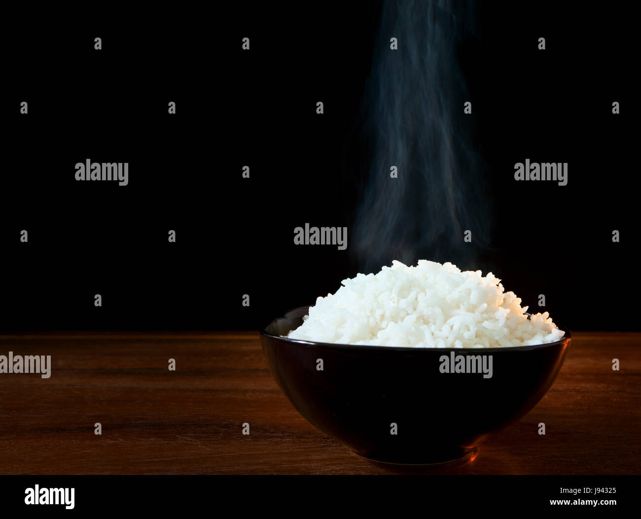 white steam rice in black ceramic bowl with smoke on black use for food ...