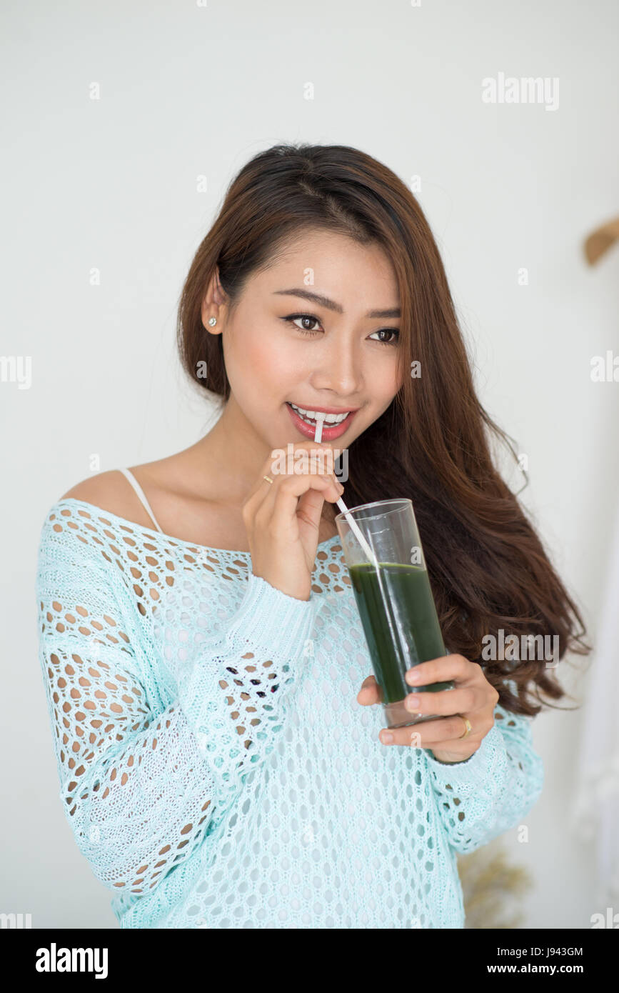 Pretty Young Asian Woman Drinking Green Fresh Vegetable Juice Or