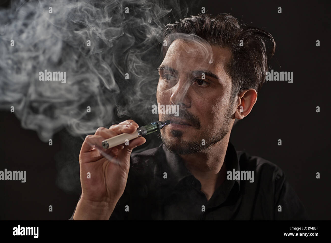 Portrait of man who is smoking electronic cigarette Stock Photo - Alamy