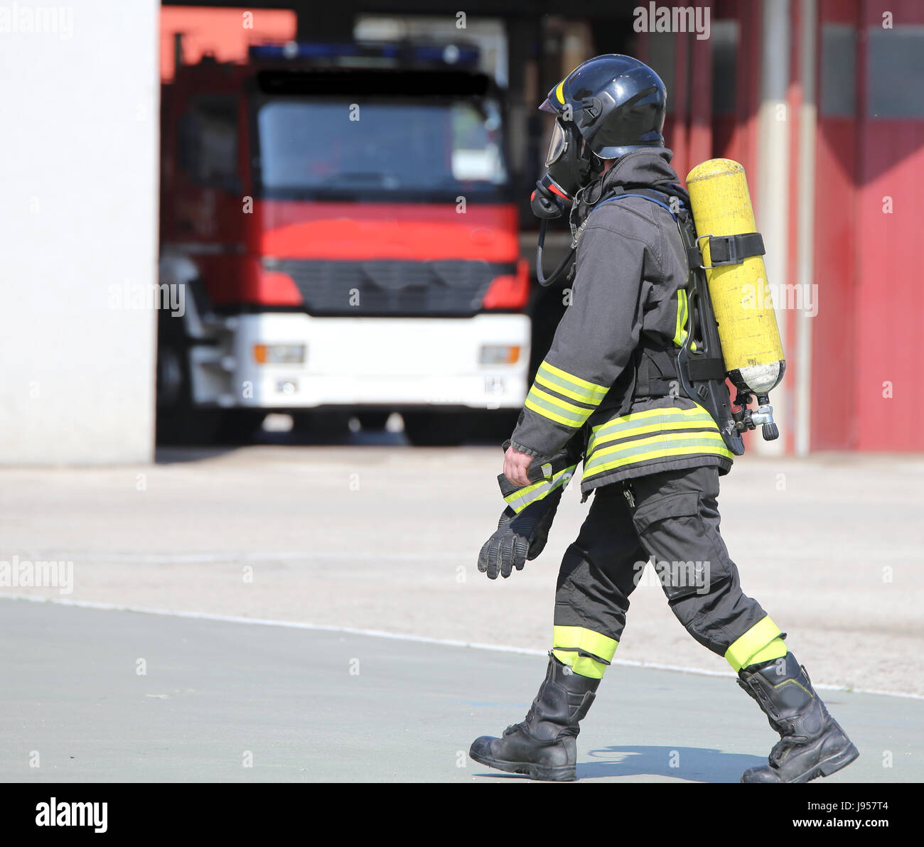 Firefighter with large yellow oxygen cylinder and automatic respirator ...