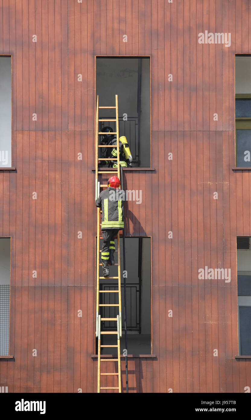 Intrepid firefighters on the wooden ladder during firefighting in the ...
