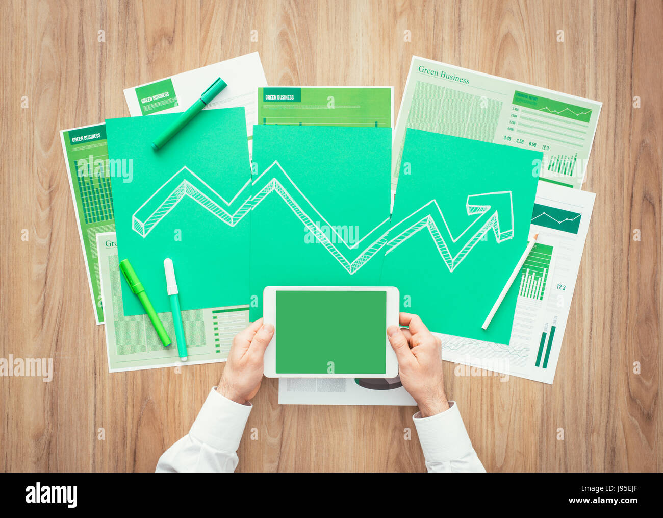Businessman drawing a financial chart with arrow on green sheets and ...