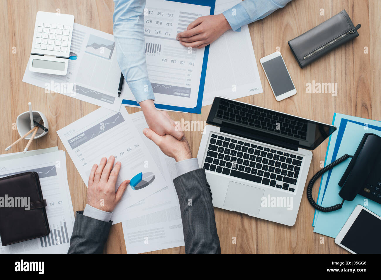 Business people working at office desk and giving an handshake ...
