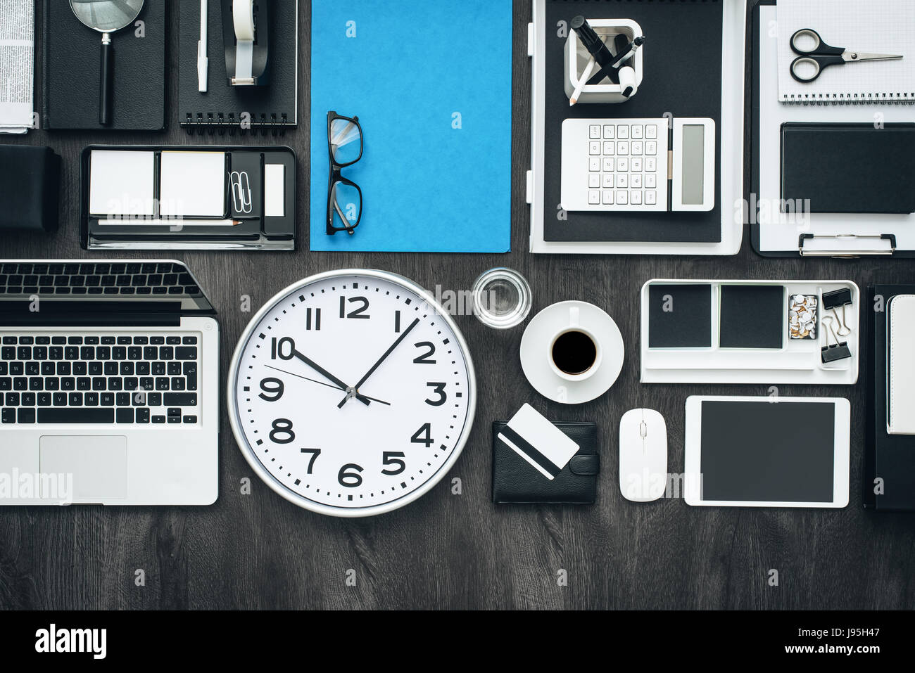 Corporate business desktop with laptop, office accessories and a clock ...