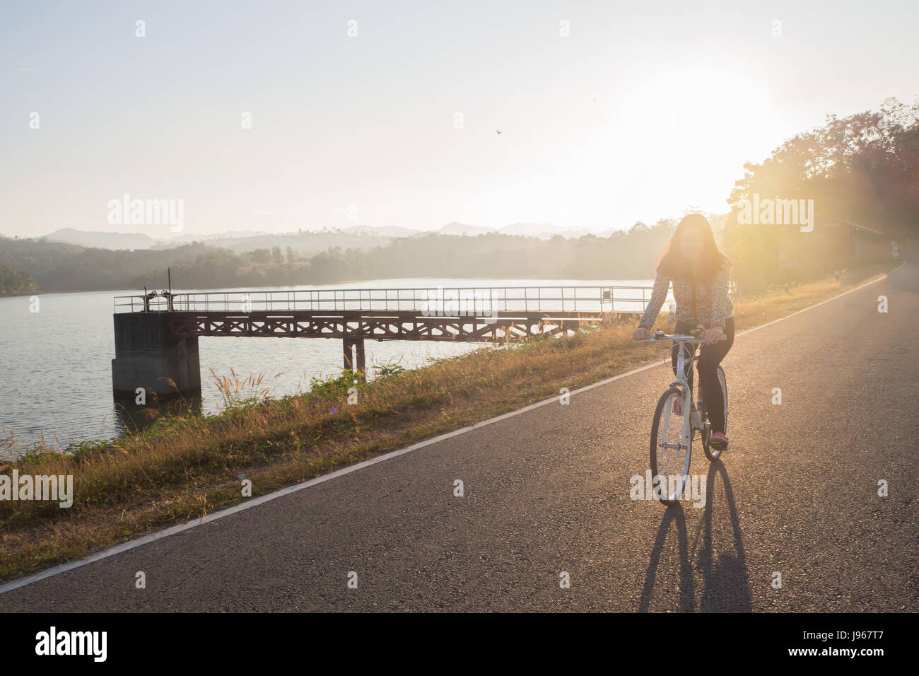 young woman ride bicycle on load dam in morning, concept of Asian ...