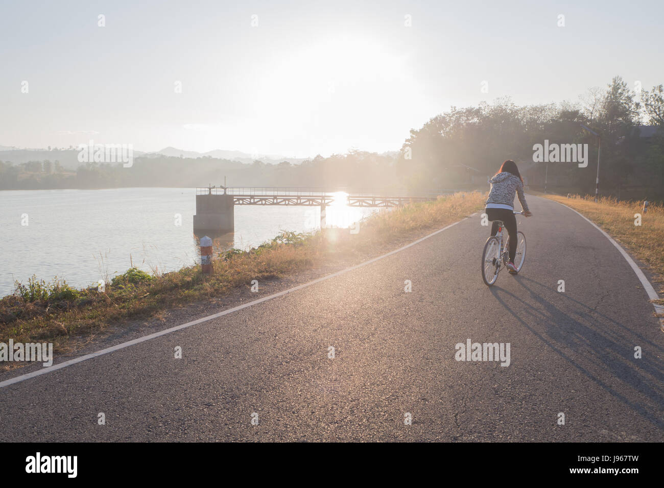young woman ride bicycle on load dam in morning, concept of Asian ...