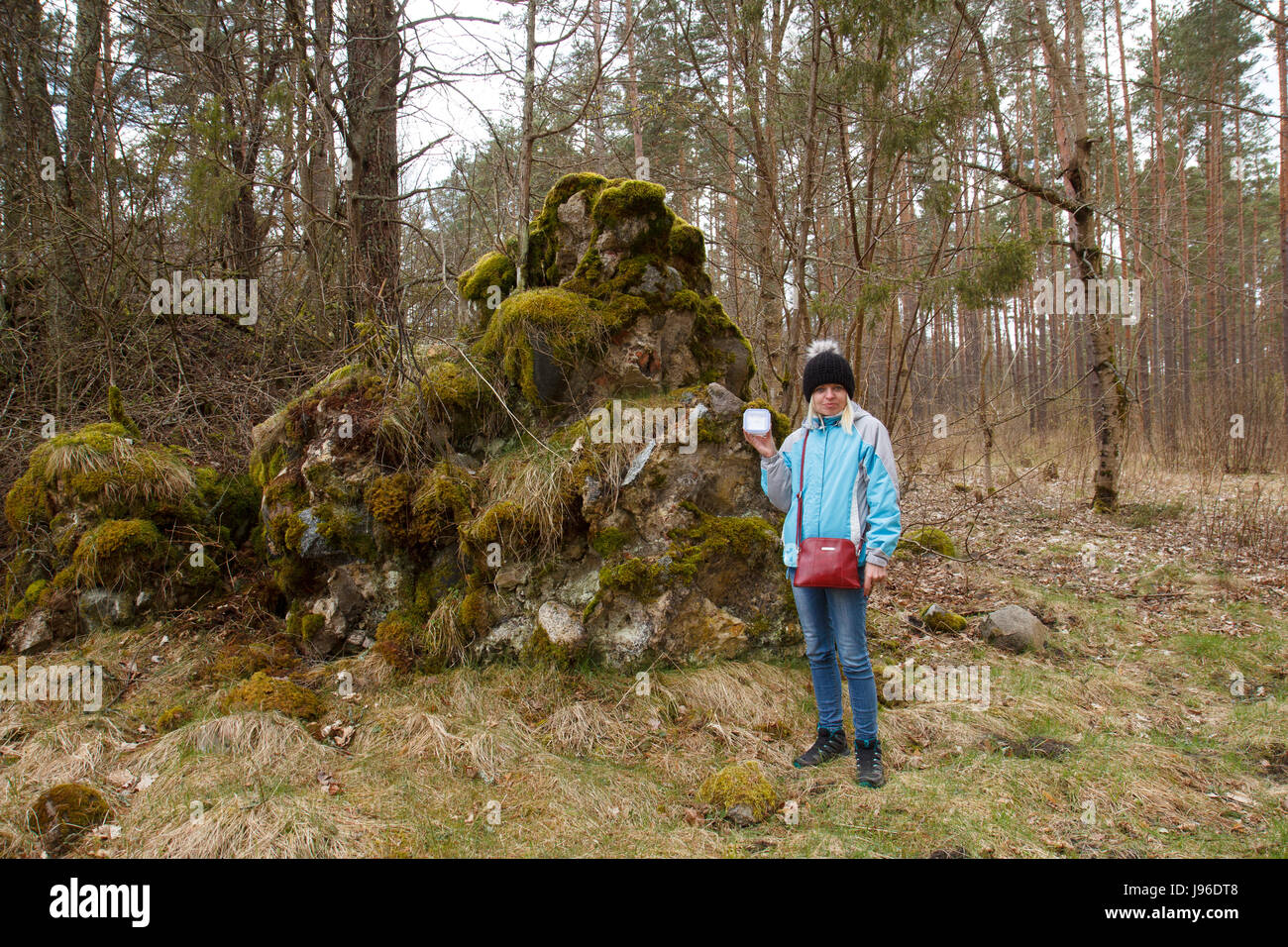 A female geocacher holding a box by a big rock Stock Photo - Alamy