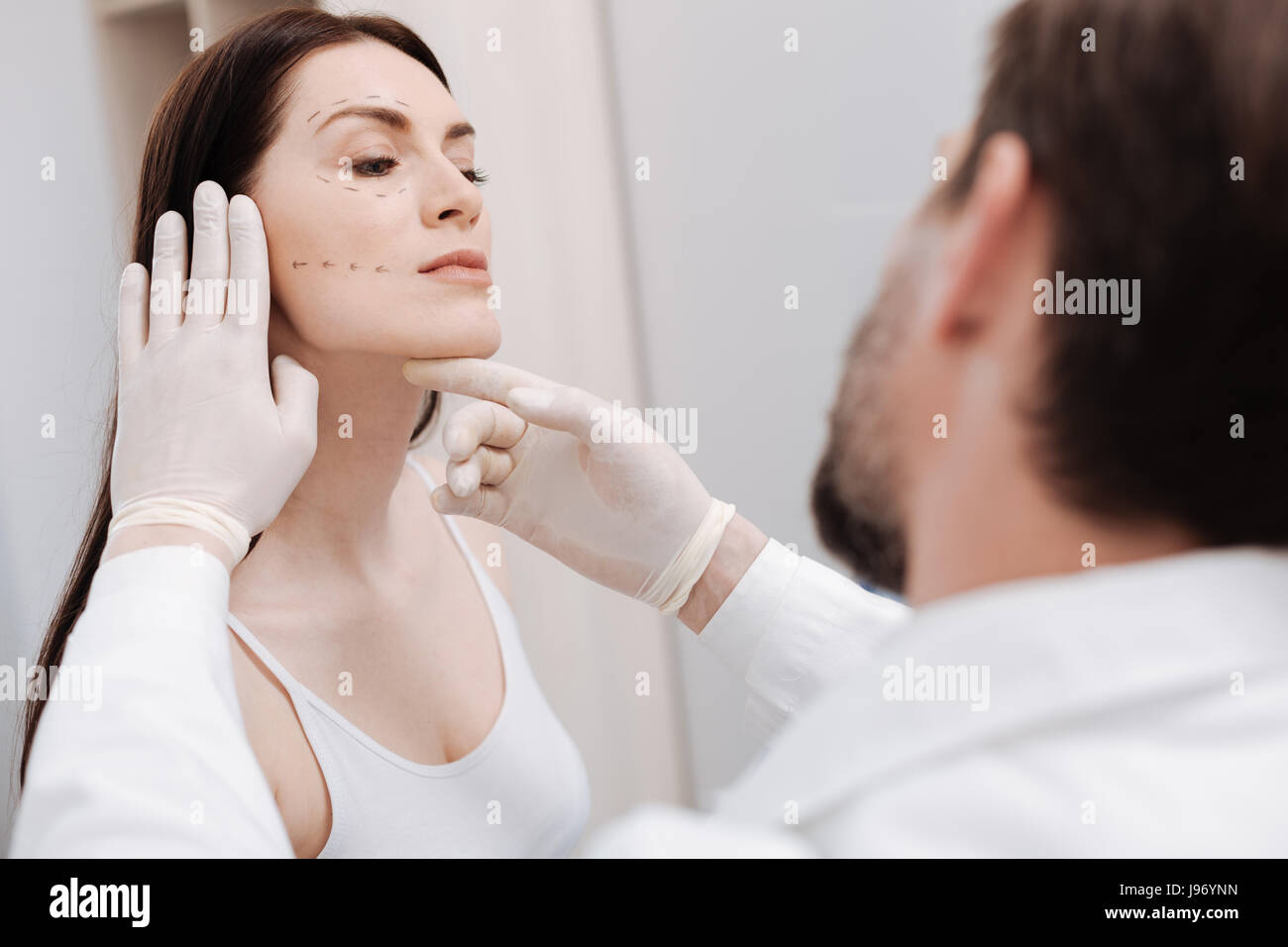 Remarkable tender plastic surgeon studying patients face from different ...