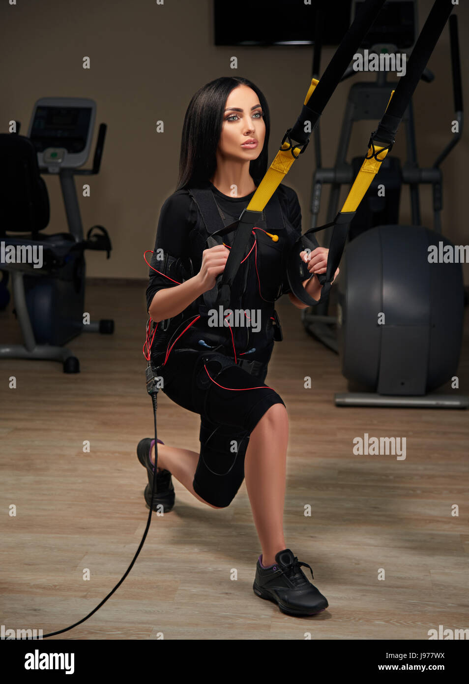 Brunette girl in Electrical Muscular Stimulation suit doing squat ...