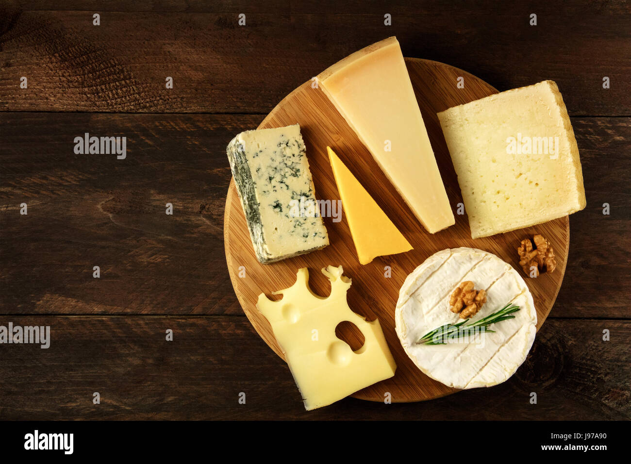 An overhead photo of a selection of cheeses, shot from above on a dark ...