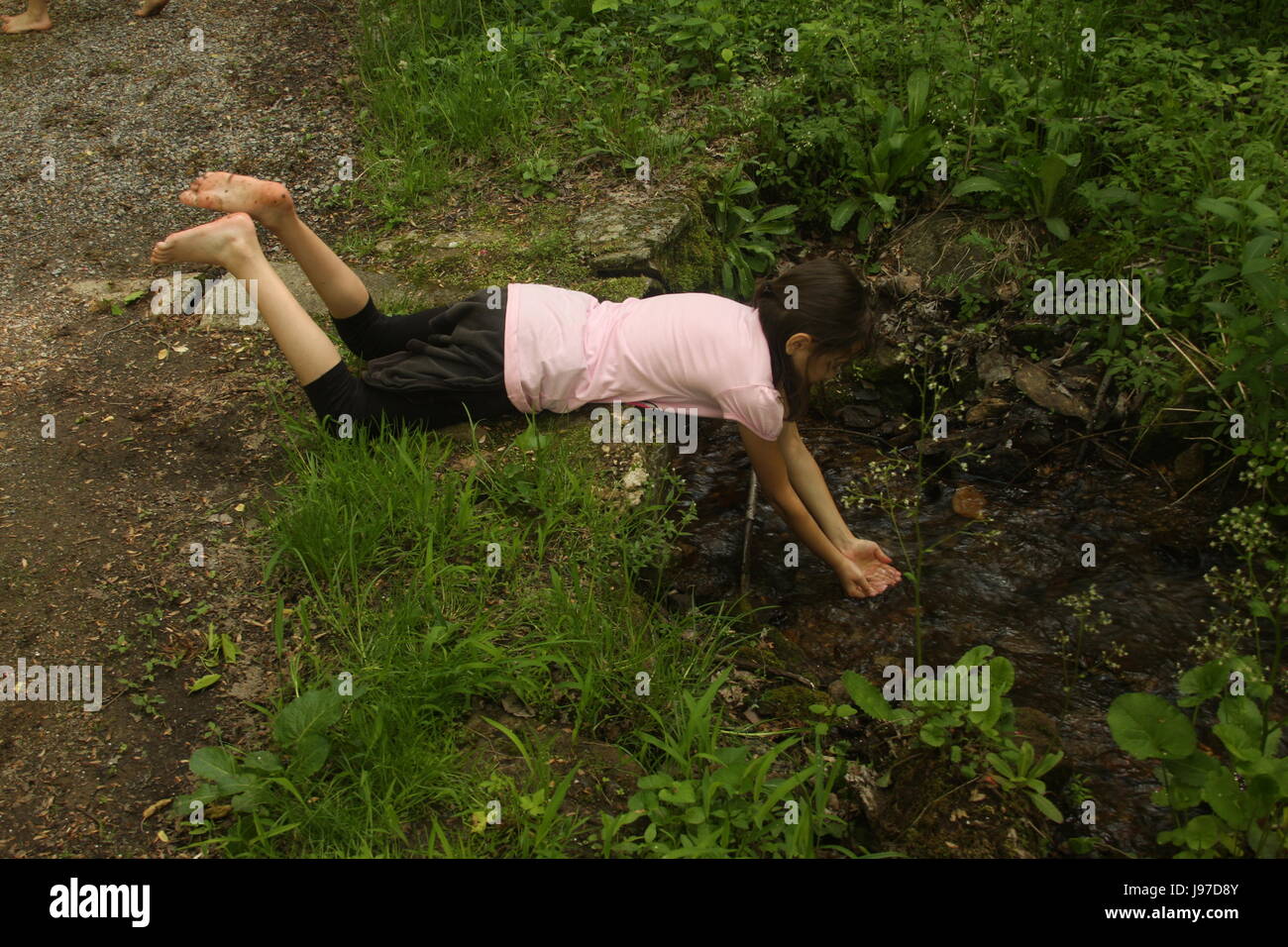 Little girl drinking water from mountain spring Stock Photo - Alamy