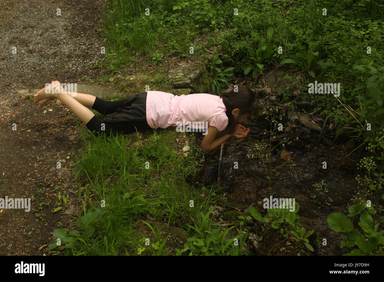 Little girl drinking water from mountain spring Stock Photo - Alamy