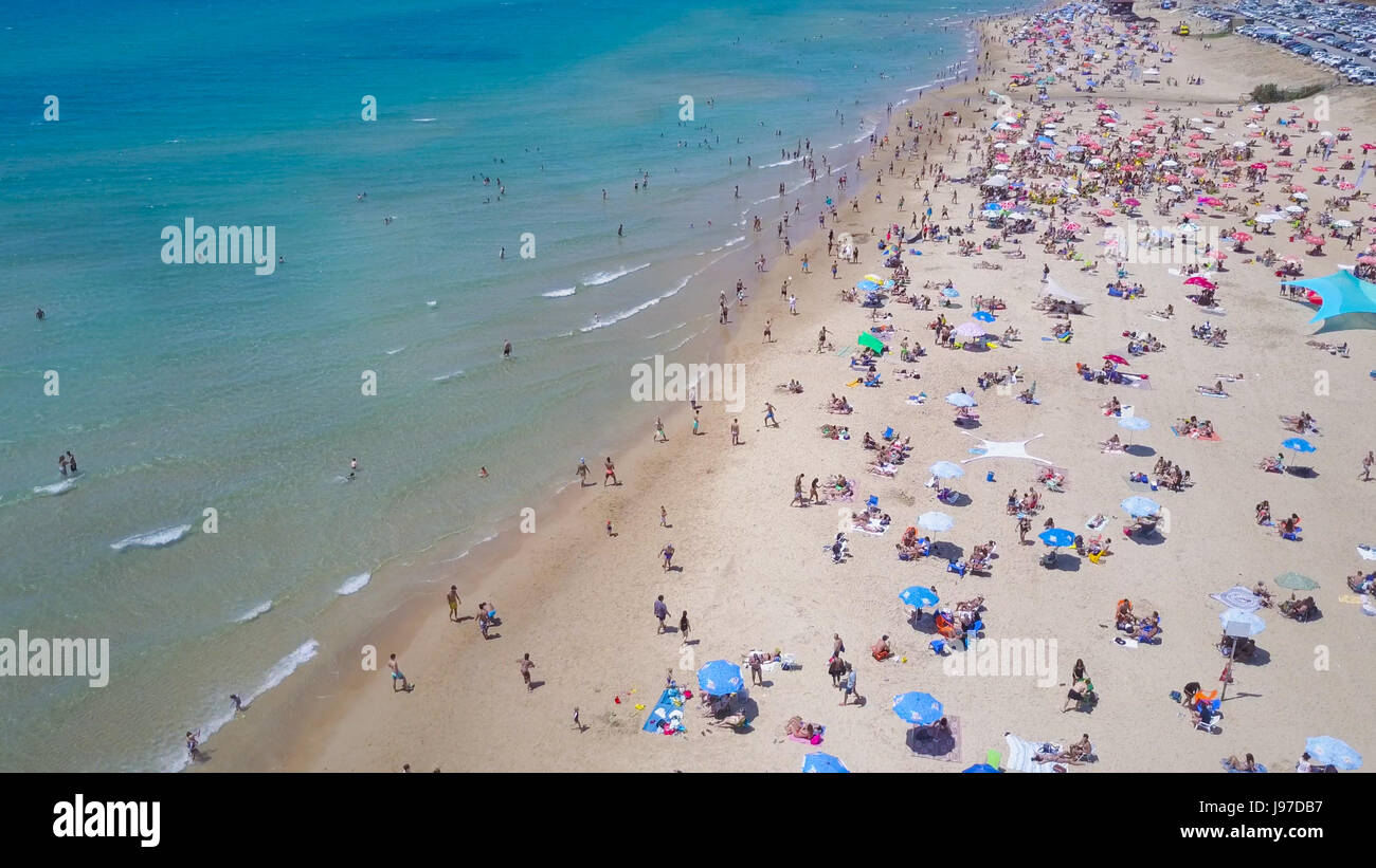 Crowded public beach with people and colourful umbrellas Stock Photo ...