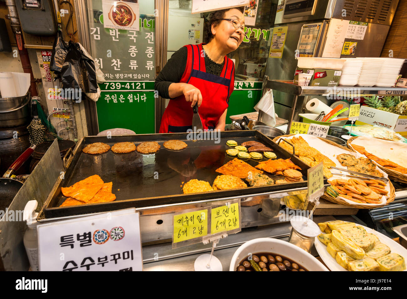 A woman selling a variety of small pancakes (Jeon) at a food stall in ...
