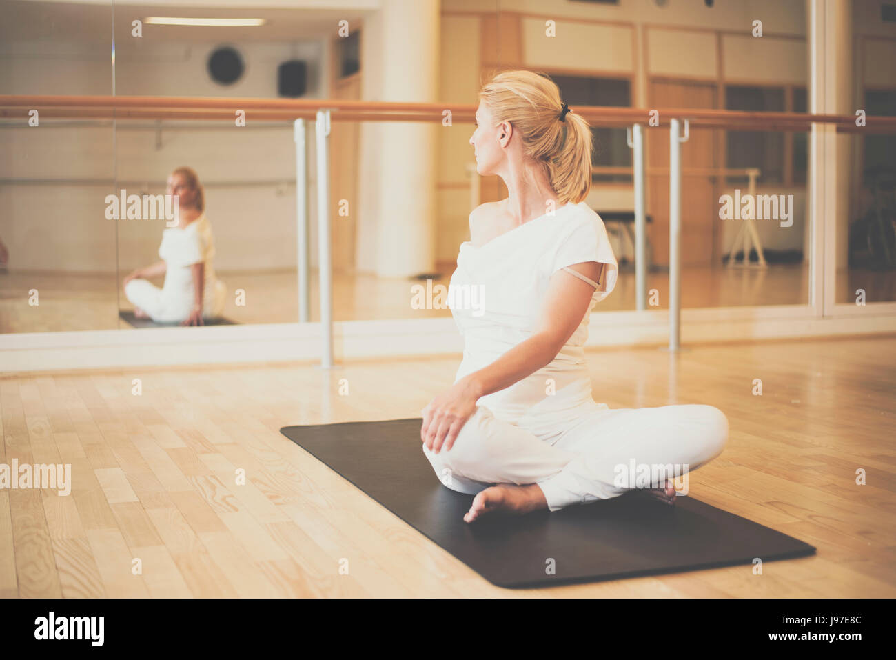 Woman practicing yoga in the lotus twisting pose Stock Photo - Alamy