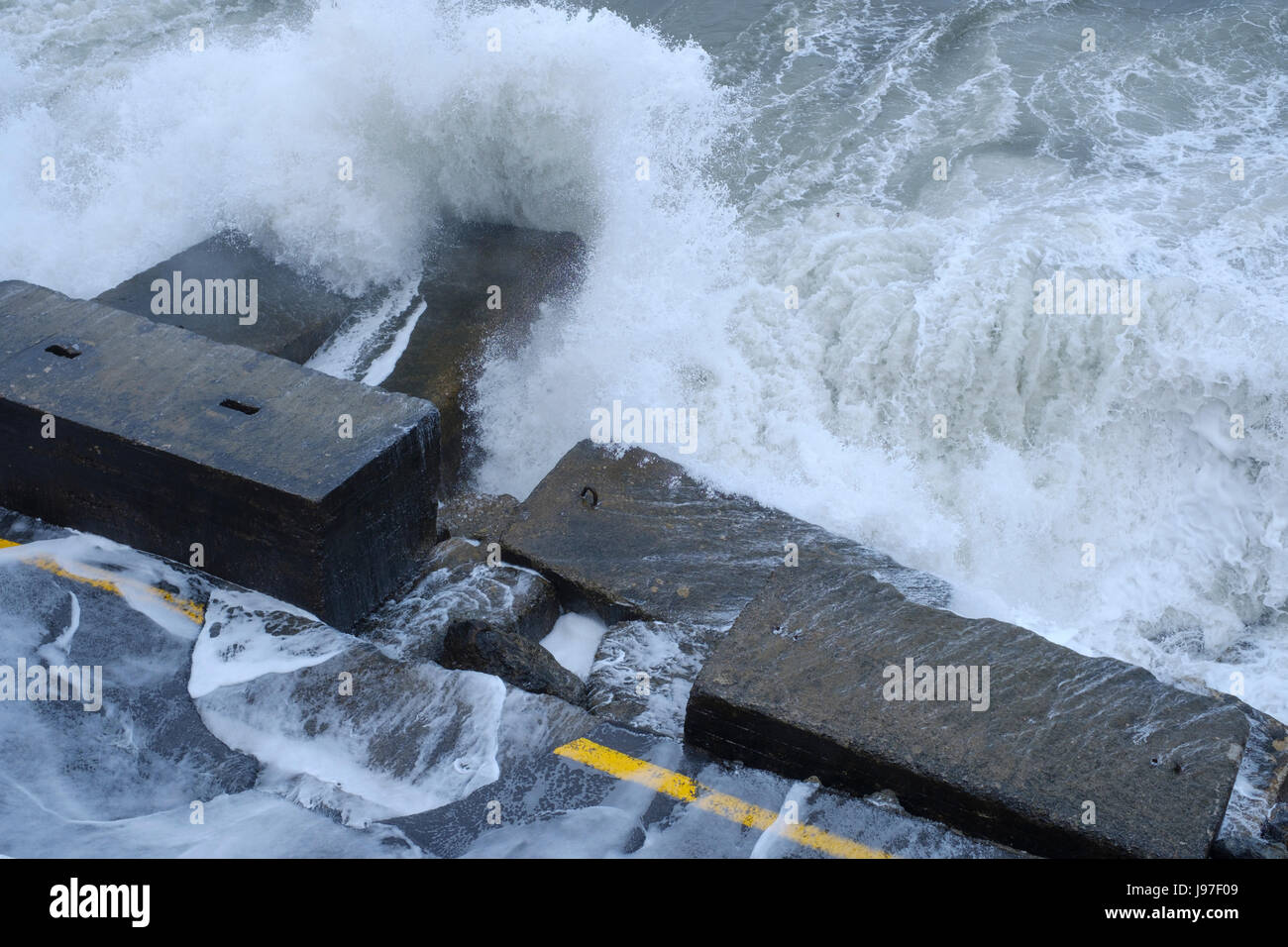 High waves caused by a heavy storm hit the quayside and destroy a paved ...
